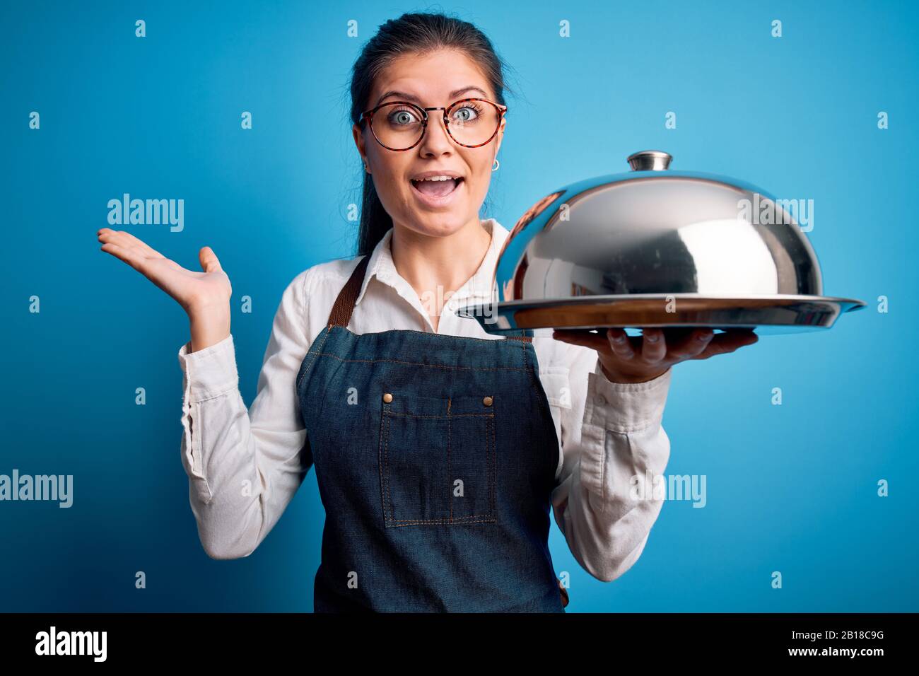 Young beautiful waitress woman with blue eyes holding tray with dome ...