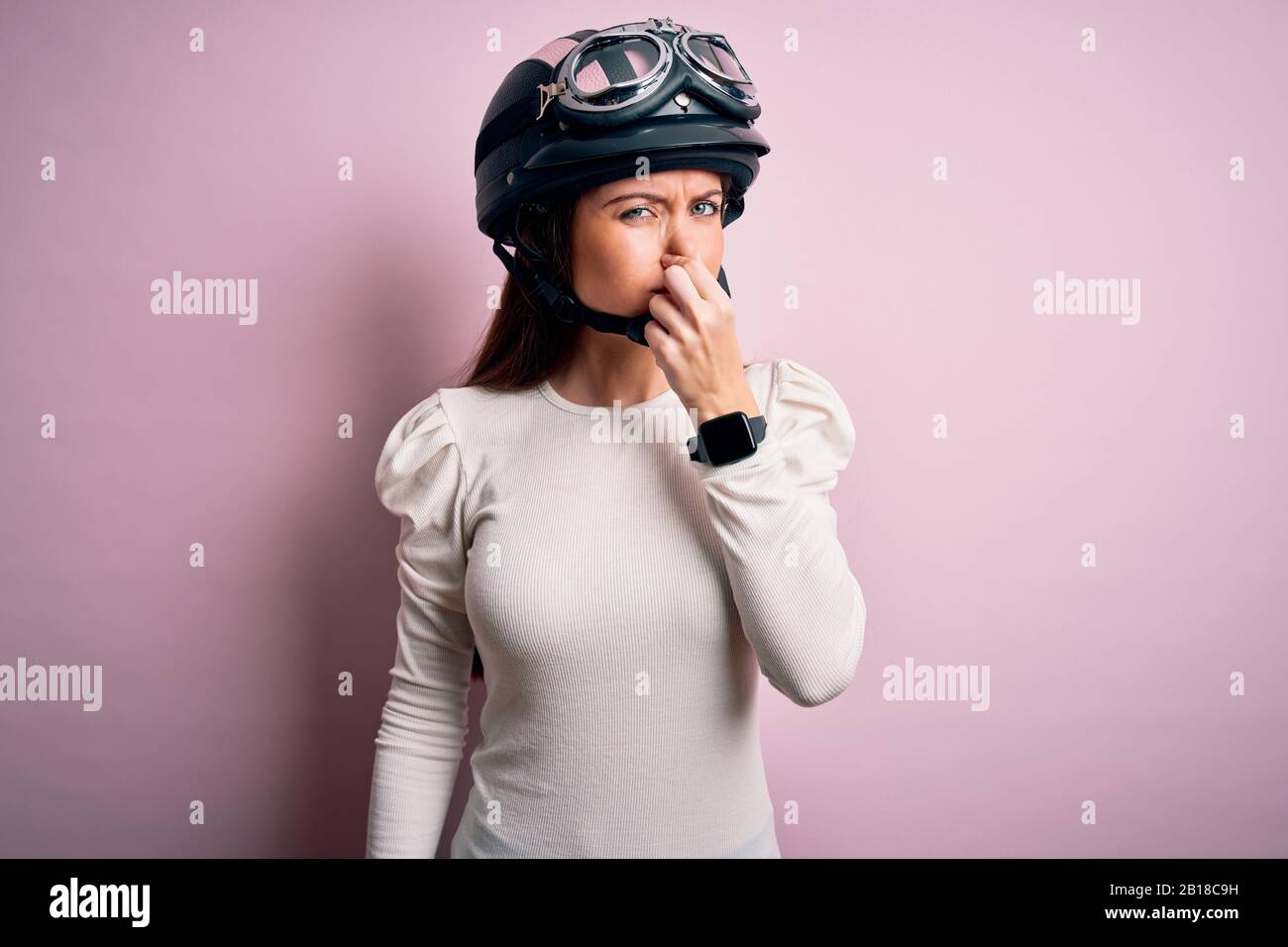 Young beautiful motorcyclist woman with blue eyes wearing moto helmet ...