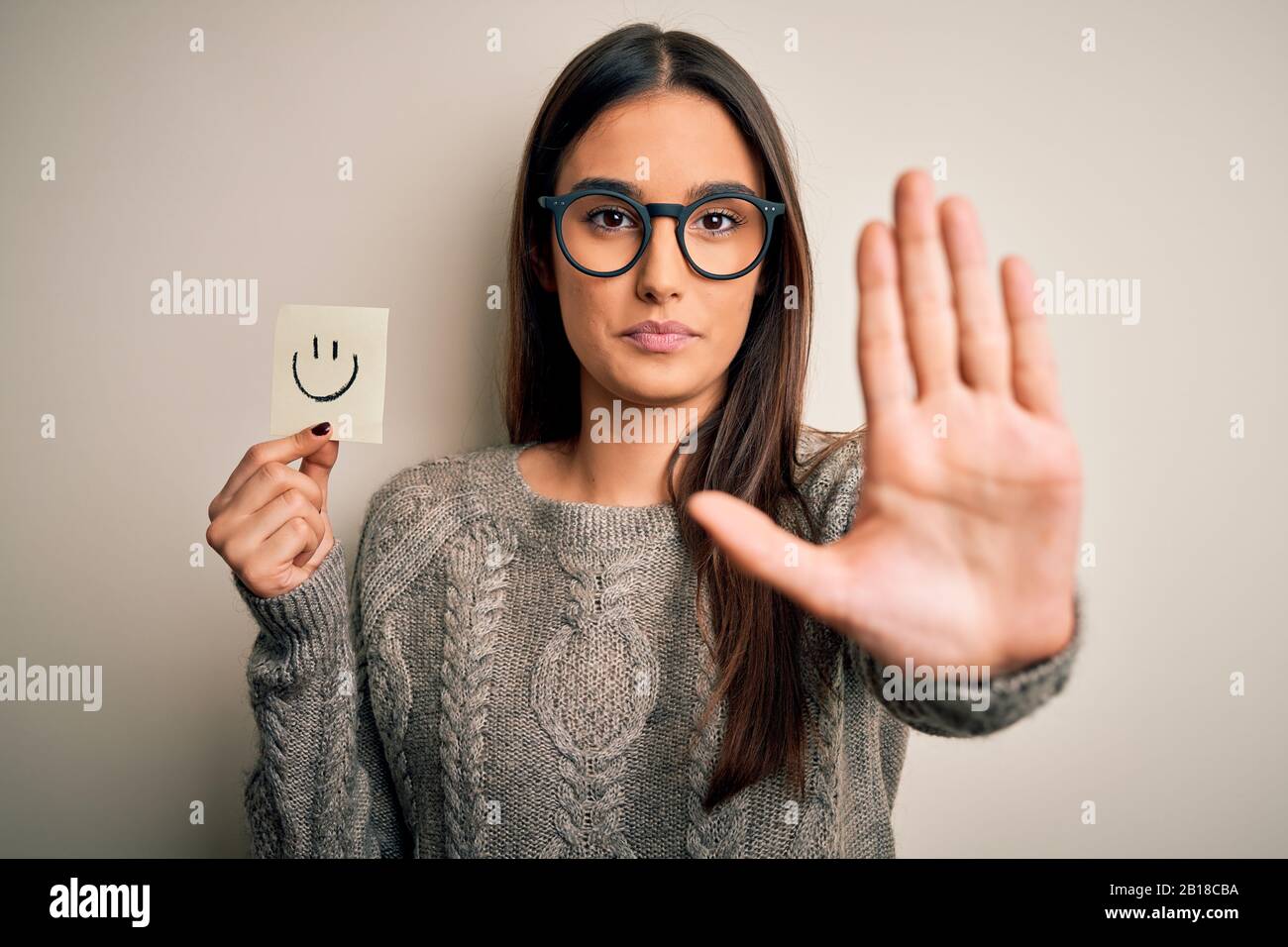 Young beautiful brunette woman wearing glasses holding paper with smile ...