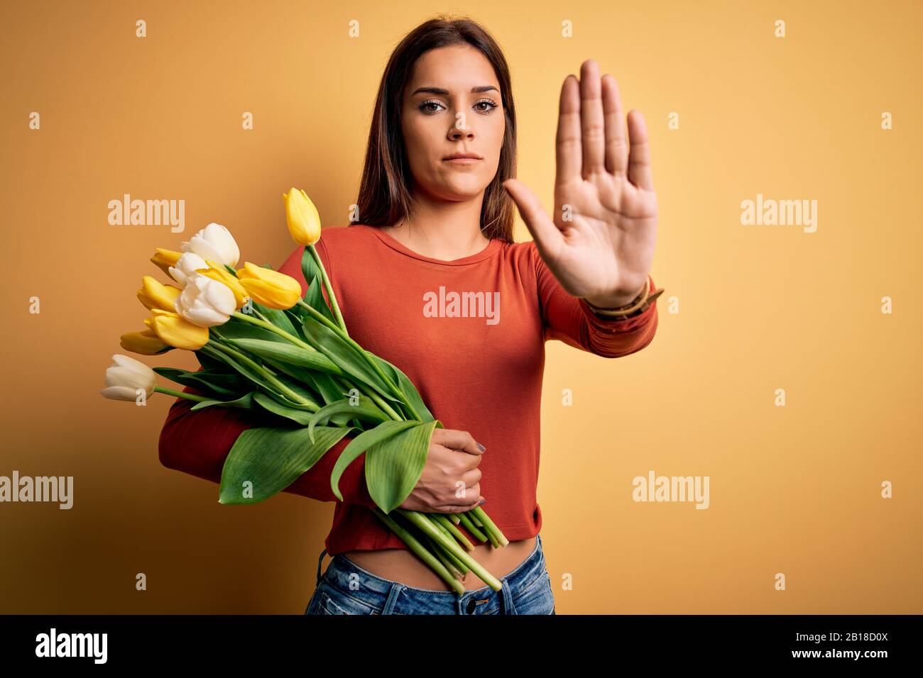 Young beautiful brunette woman holding bouquet of tulips flowers over ...