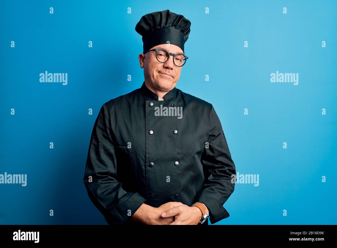 Middle age handsome grey-haired chef man wearing cooker uniform and hat ...