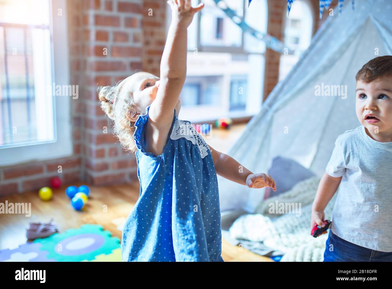 Beautiful teacher and group of toddlers playing around lots of toys at kindergarten Stock Photo ...