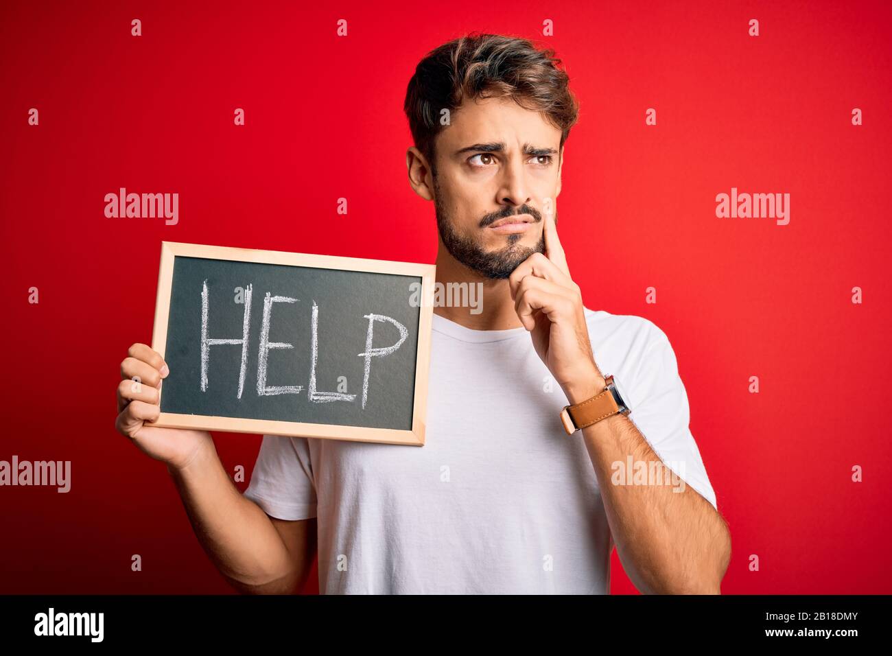 Young man with problem holding blackboard with help message over red ...