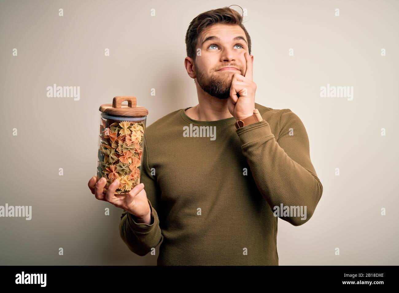 Young blond man with beard and blue eyes holding bottle of Italian dry ...