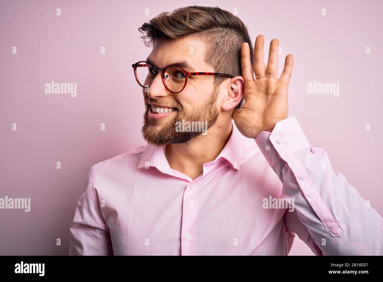 Young handsome blond man with beard and blue eyes wearing pink shirt ...