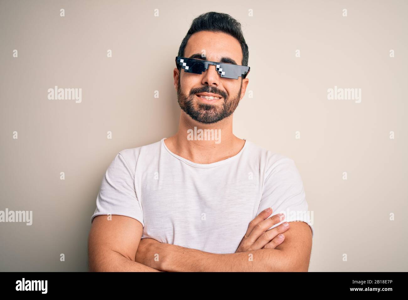 Young handsome man with beard wearing funny thug life sunglasses over ...