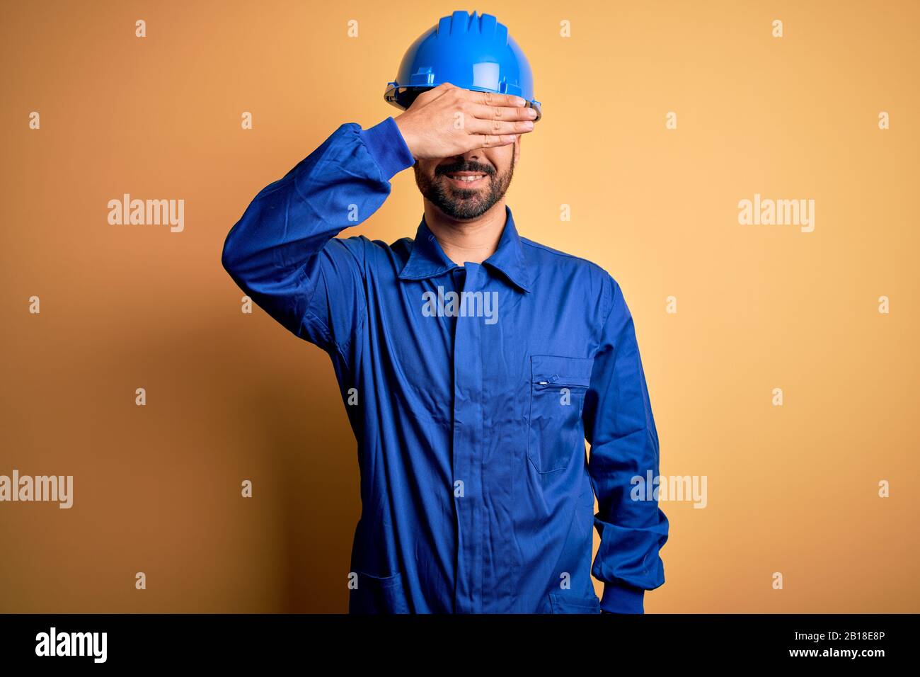 Mechanic man with beard wearing blue uniform and safety helmet over ...
