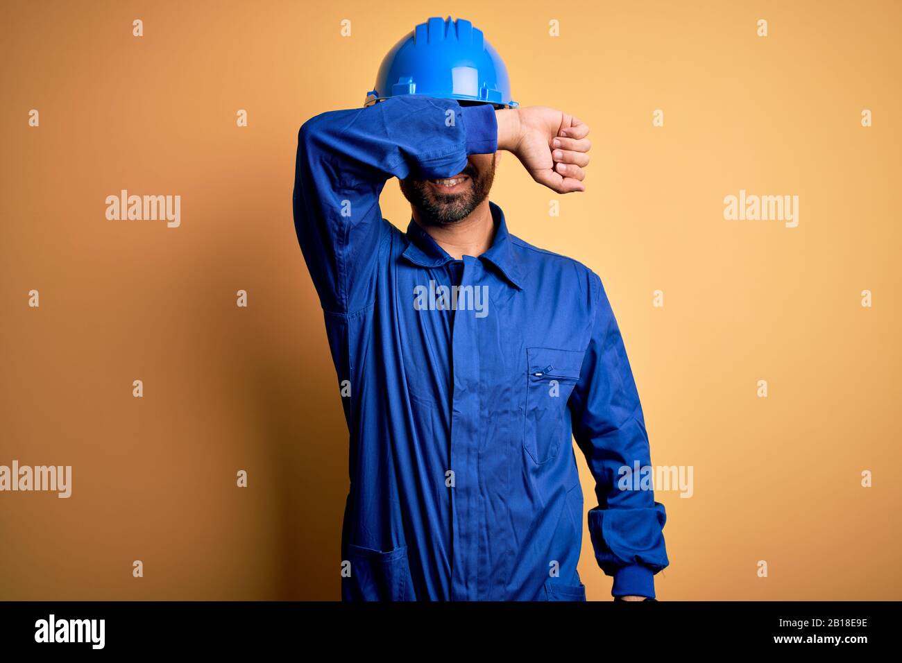 Mechanic man with beard wearing blue uniform and safety helmet over ...