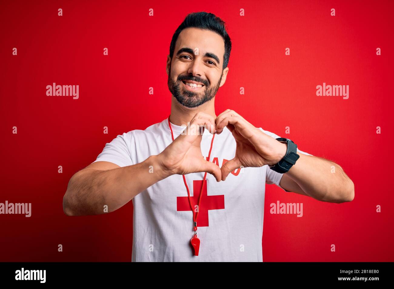 Young handsome lifeguard man with beard wearing whistle over isolated ...