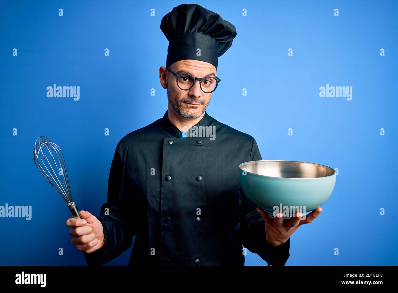 Young handsome chef man wearing cooker uniform and hat mixing using ...
