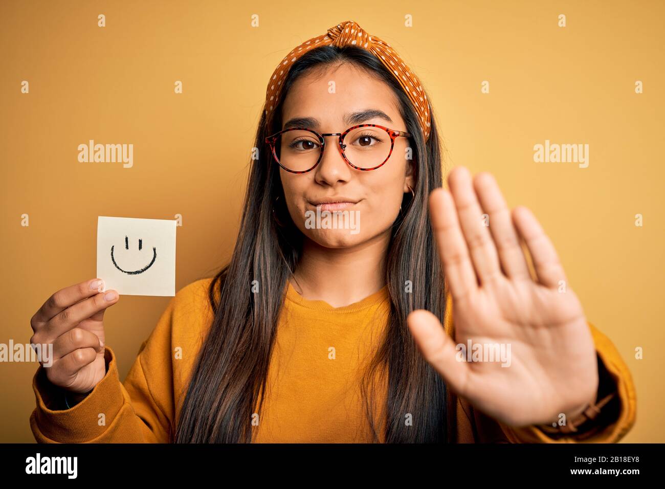 Asian woman wearing glasses holding reminder with smile emoji draw over ...