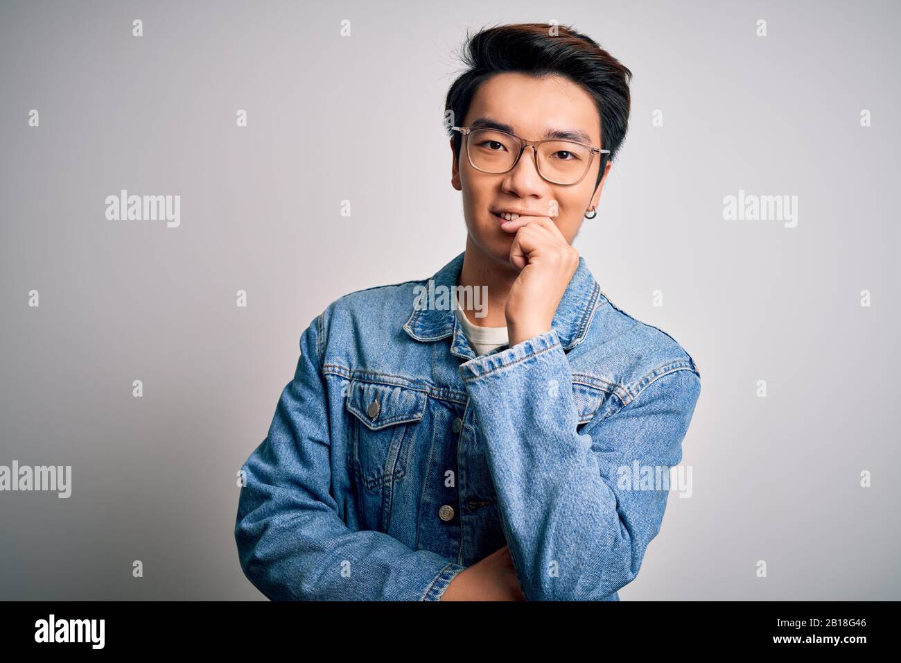 Young handsome chinese man wearing denim jacket and glasses over white ...