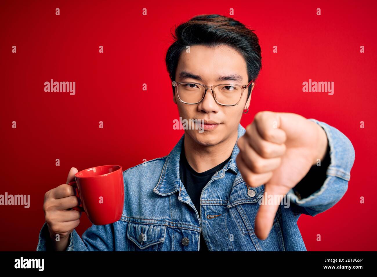 Young handsome chinese man drinking cup of coffee over isolated red ...