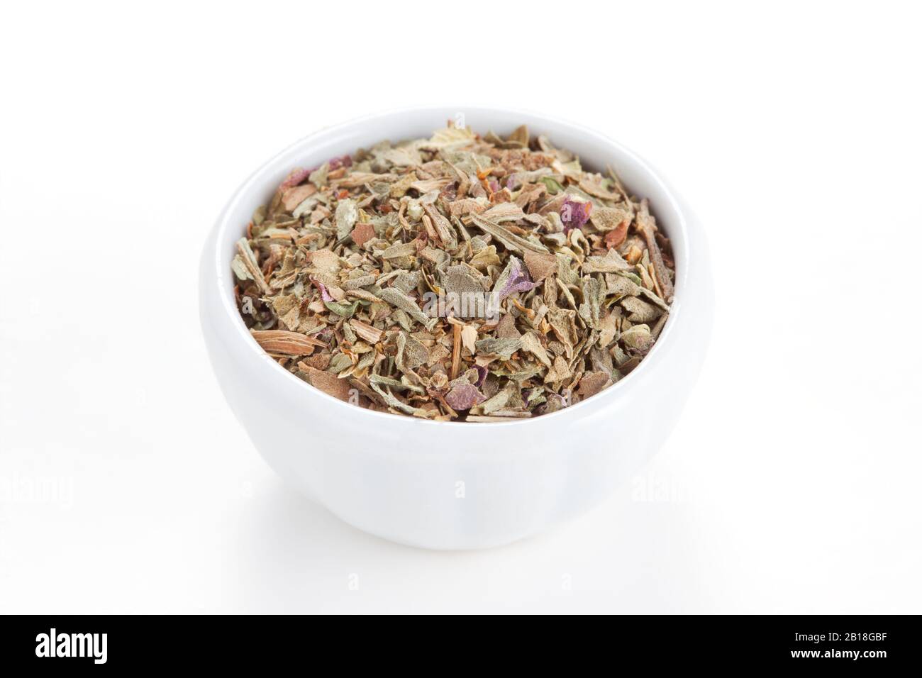 Ground dried Basil (Sweet Basil) in a white bowl on white background ...