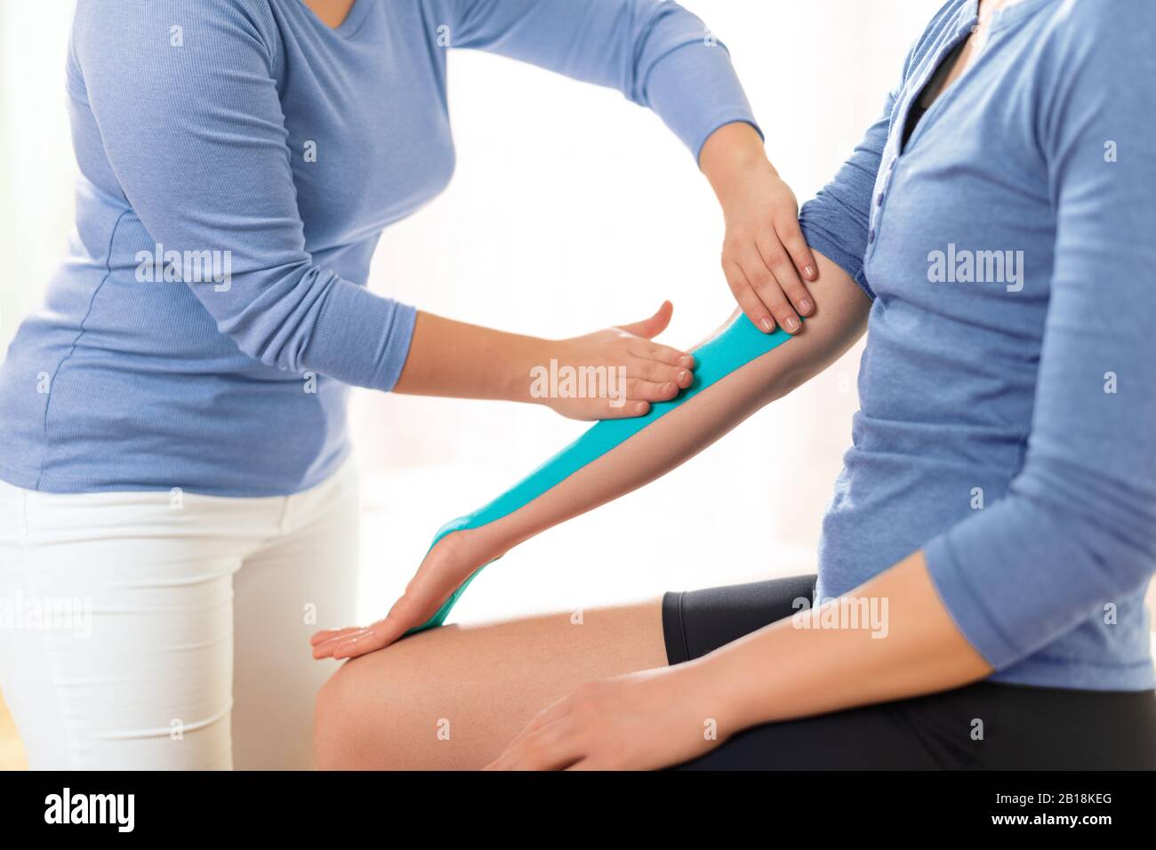 Female physiotherapist applying kinesio tape on patient's arm. Kinesiology, physical therapy ...