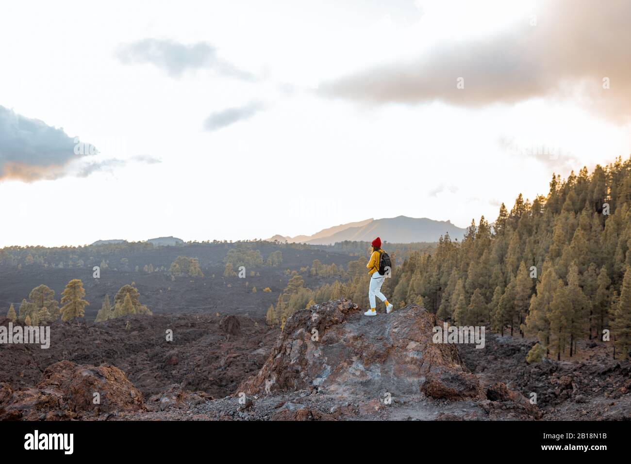 Volcanic landscapes on a sunset, woman walking on the rocky land while ...