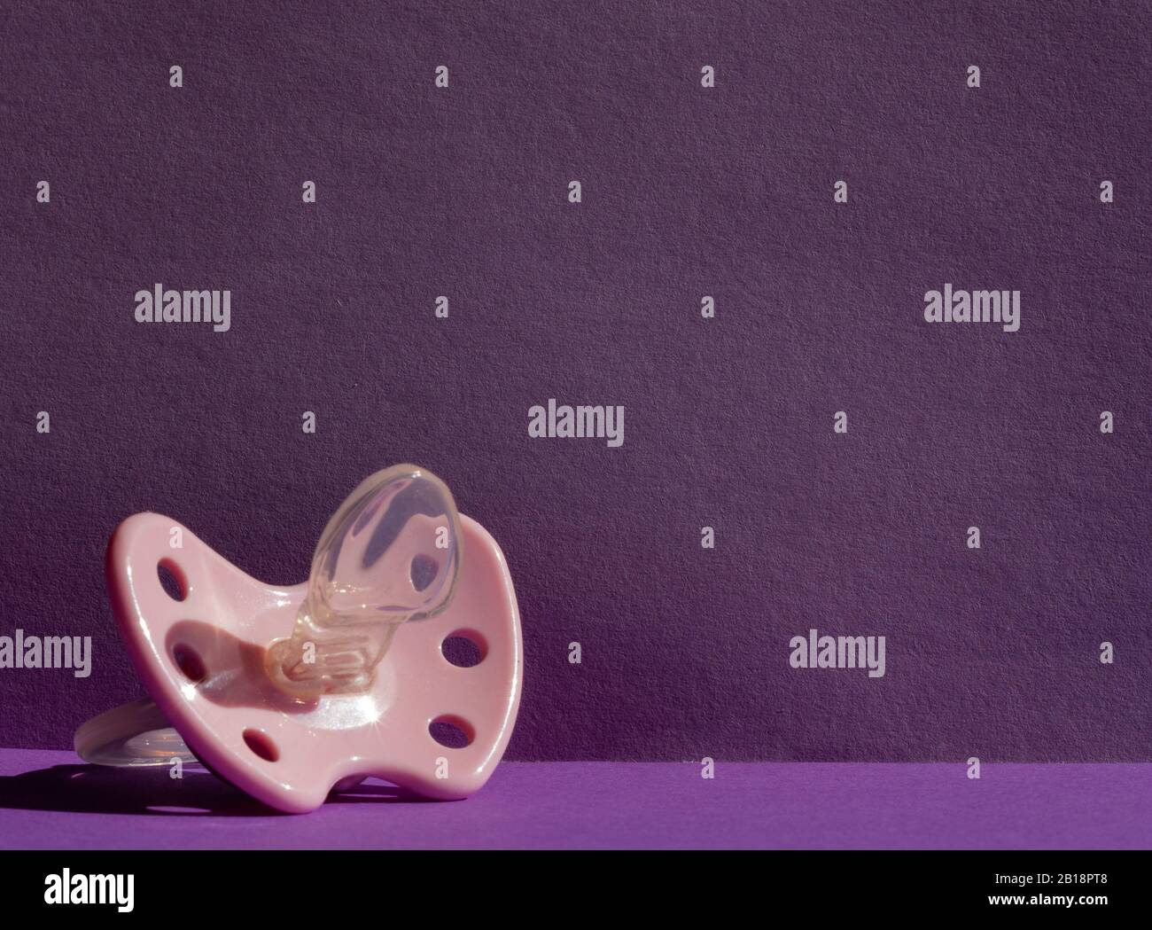 Pink baby pacifier on lilac background Stock Photo - Alamy