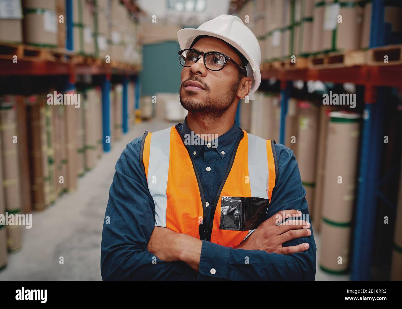 Portrait of serious supervisor in warehouse standing with folded hands ...