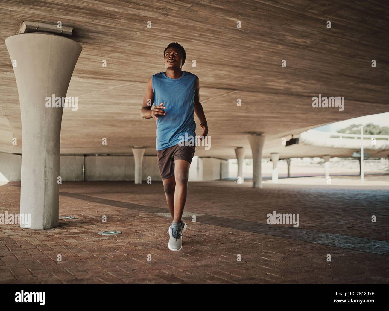 Athletic man running during morning under the concrete bridge on ...