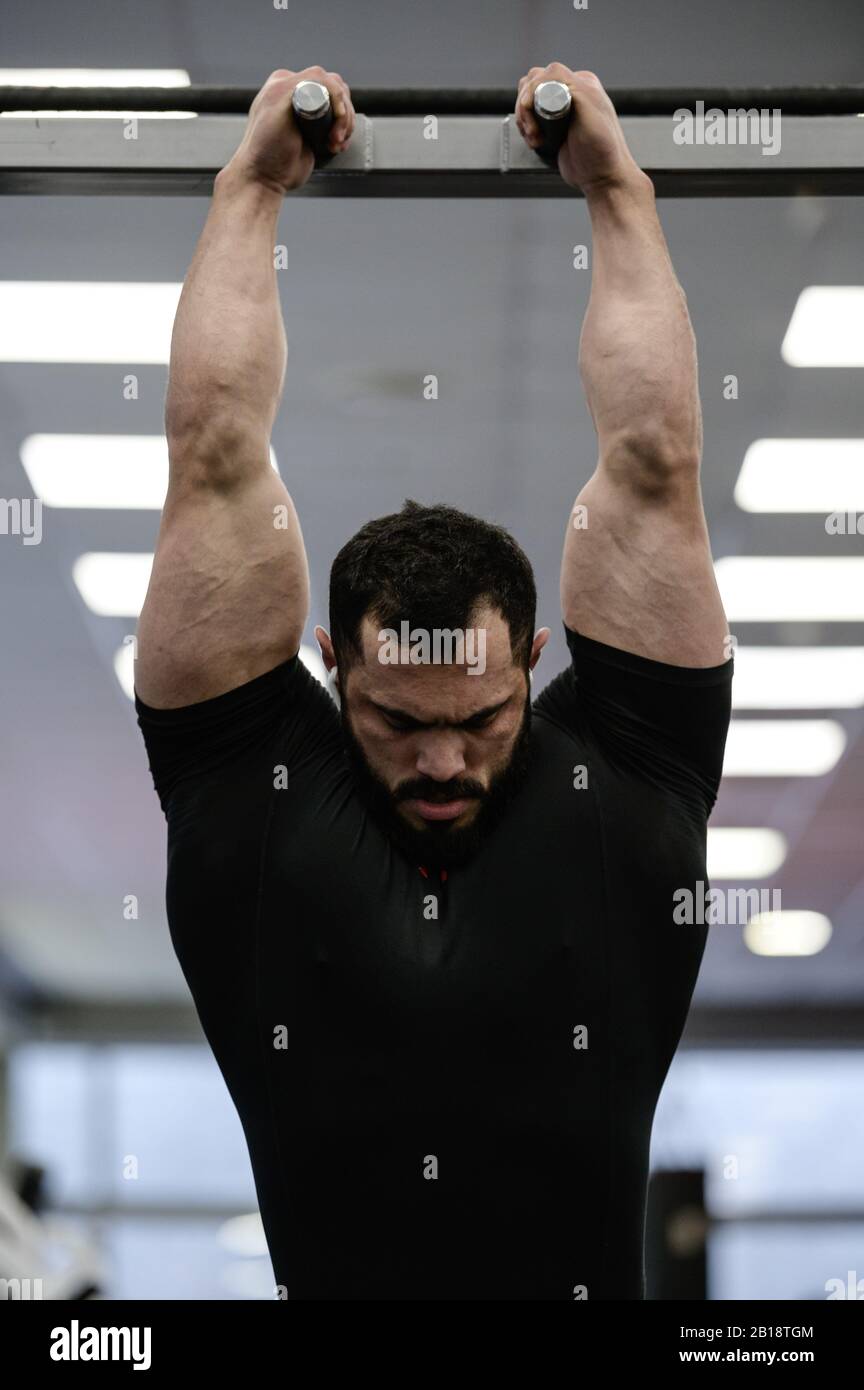 strong young man wearing black jersey and beard stretching muscles on ...