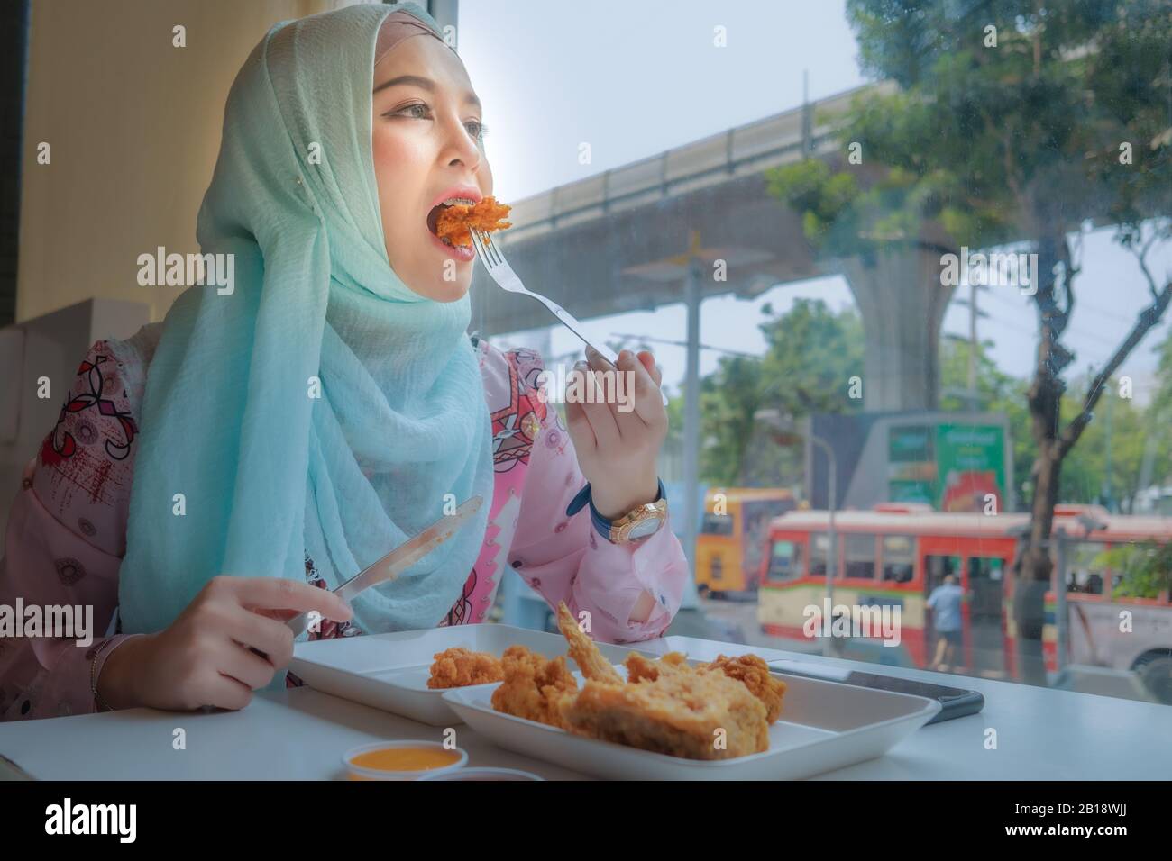 Islam lady eating fried chicken in restaurant beside the road in ...