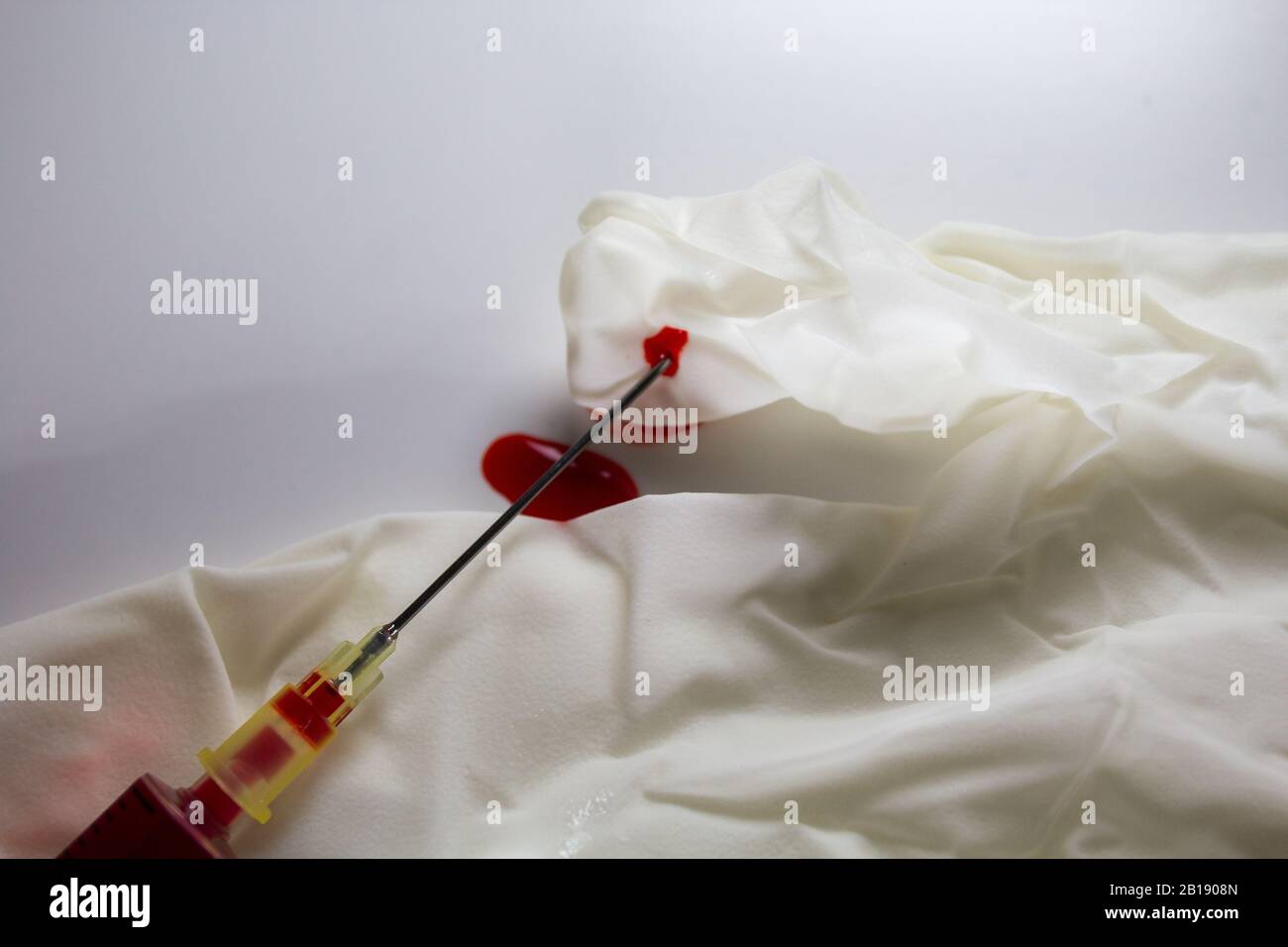 Close-up of a syringe with injection needle and artificial blood on ...