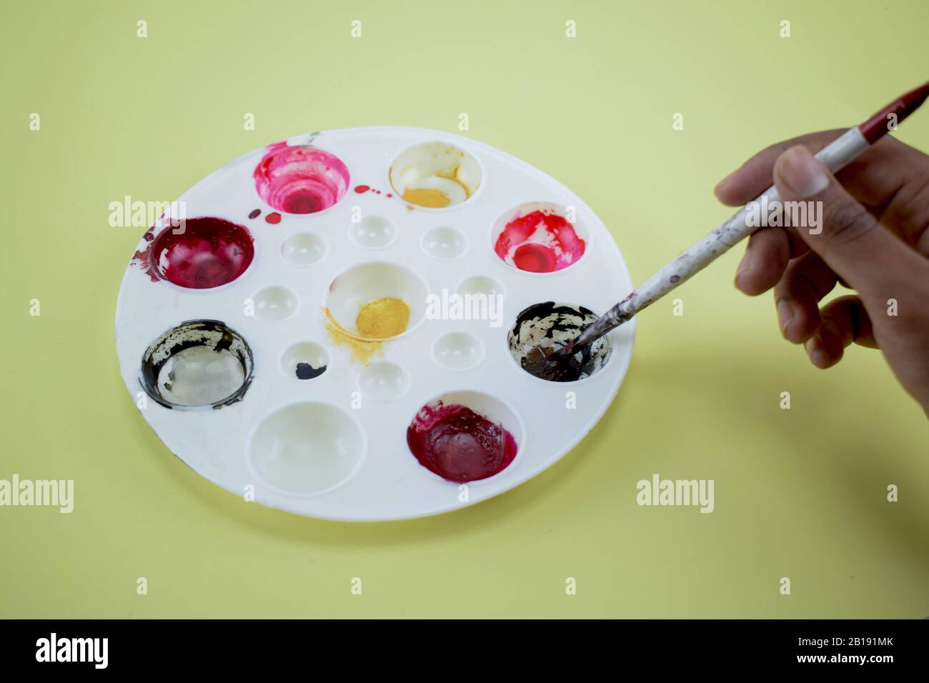 A person taking some paint with a brush from a color pallet to paint ...