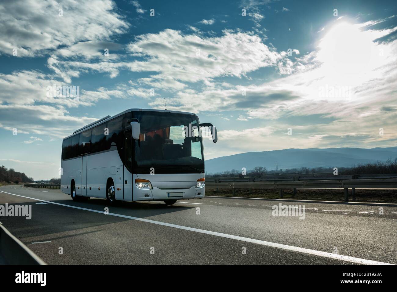 White Modern comfortable tourist bus driving through highway at bright ...