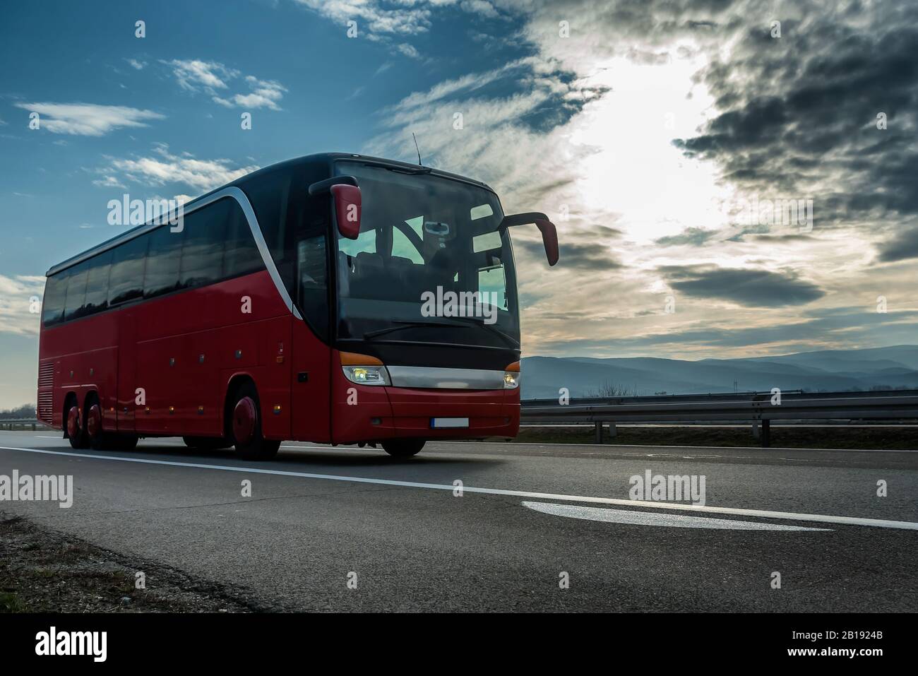 Red Modern comfortable tourist bus driving through highway at bright ...