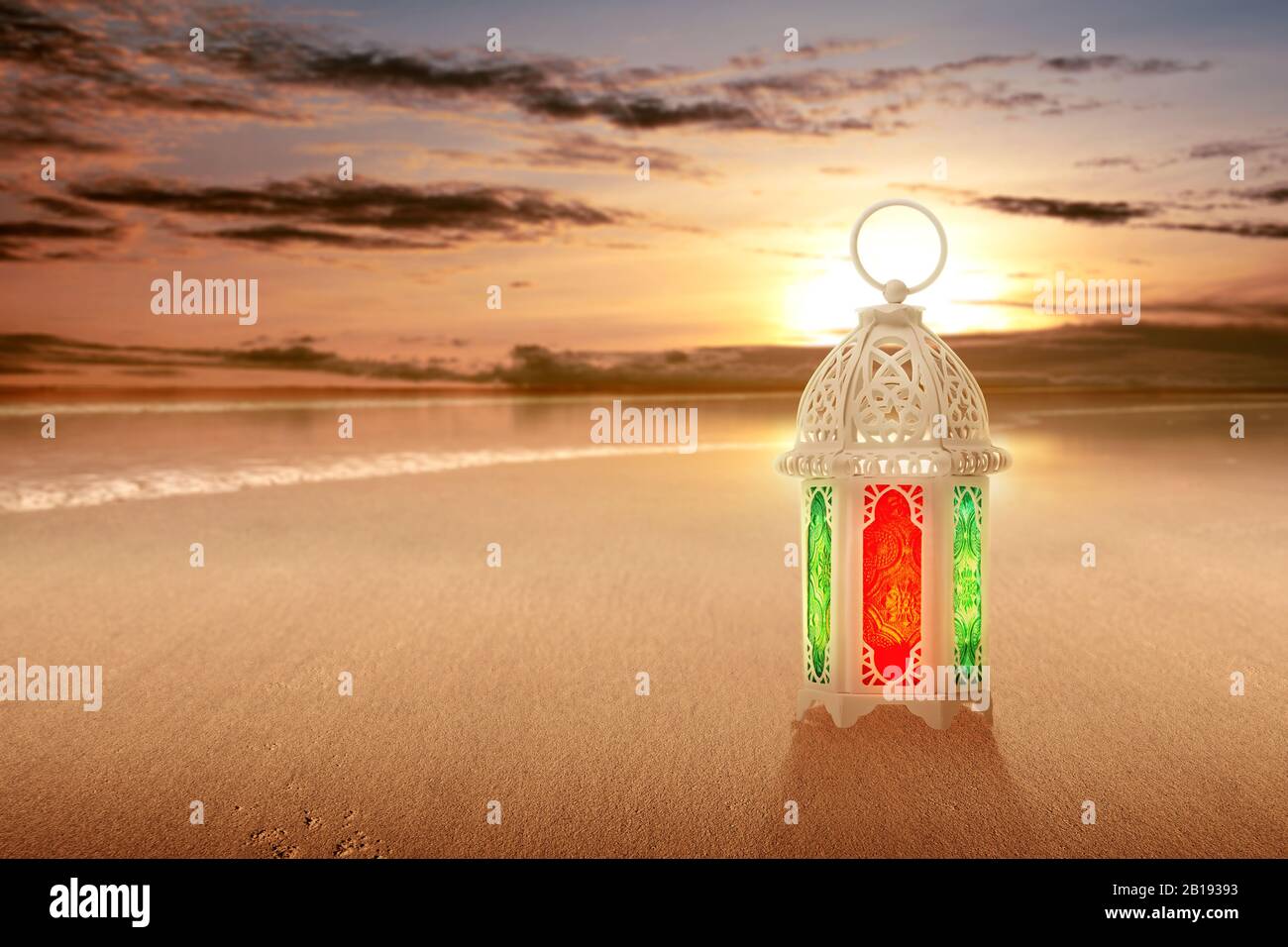 Arabic lamp with colorful light on the sandy beach with the sunset sky ...