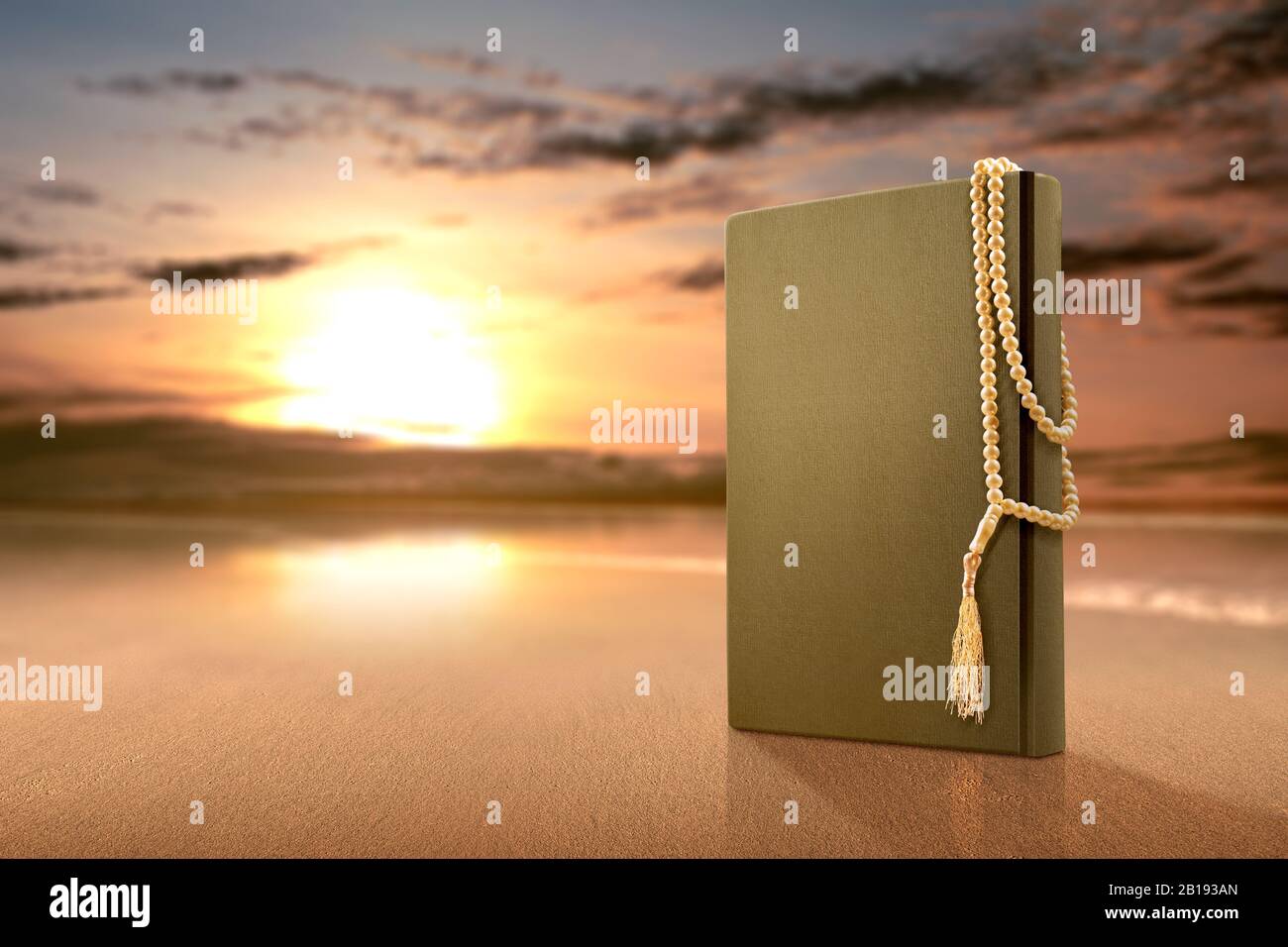 Quran and prayer beads on the sandy beach with the sunset sky ...