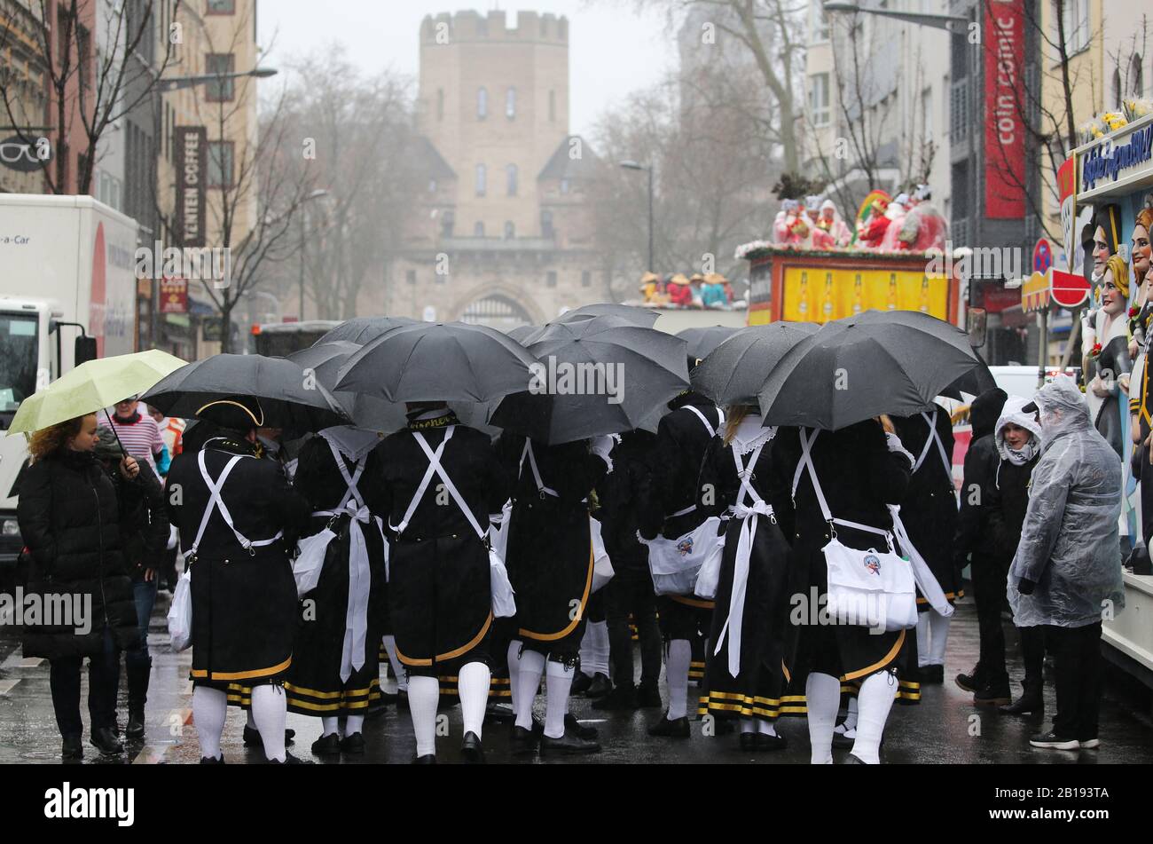 Cologne, Germany. 24th Feb, 2020. Under umbrellas a group is walking ...