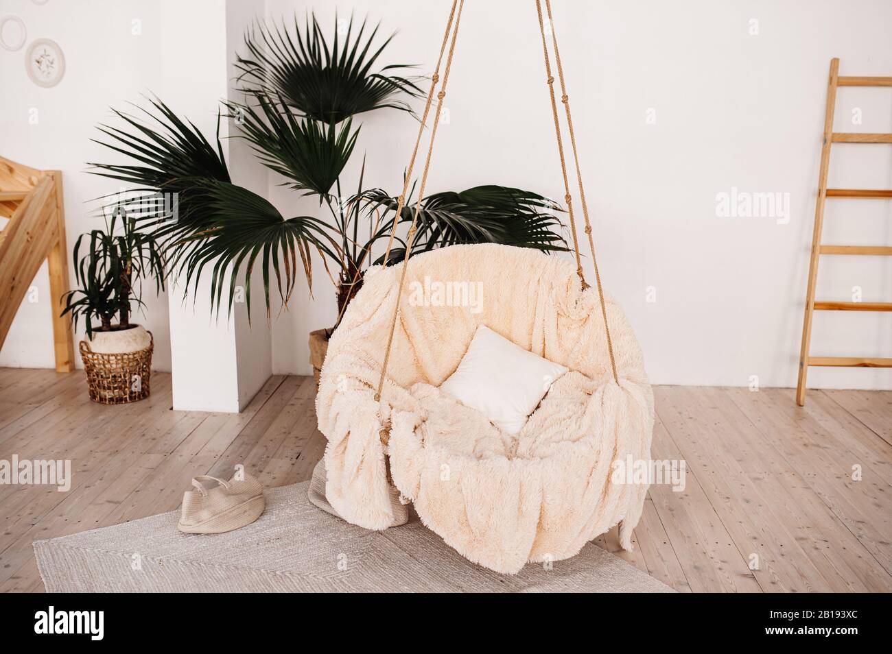 Hanging swing on ropes in the home room with plush beige plaid and ...