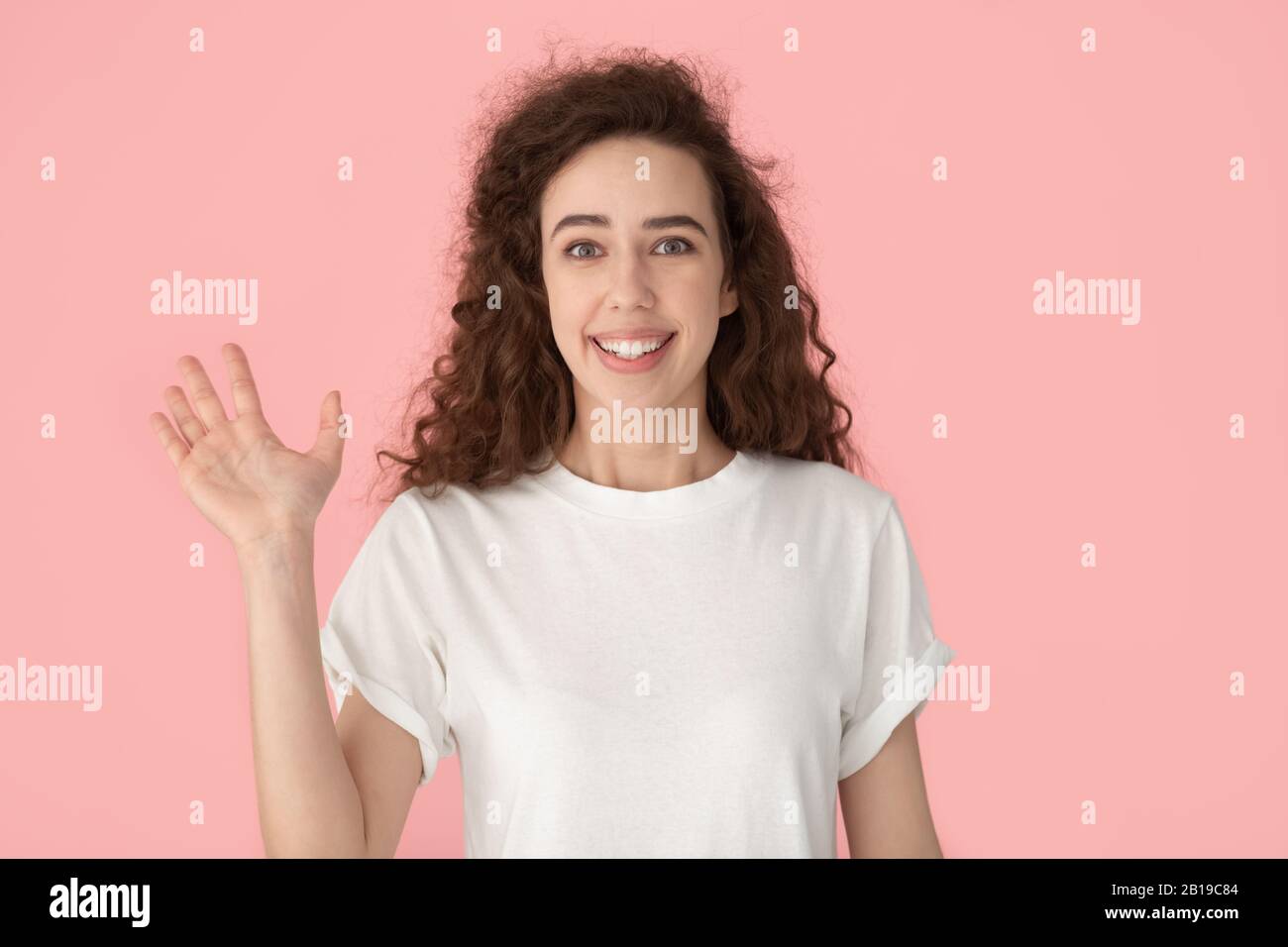 Young smiling lady waving hand, making hello gesture Stock Photo - Alamy