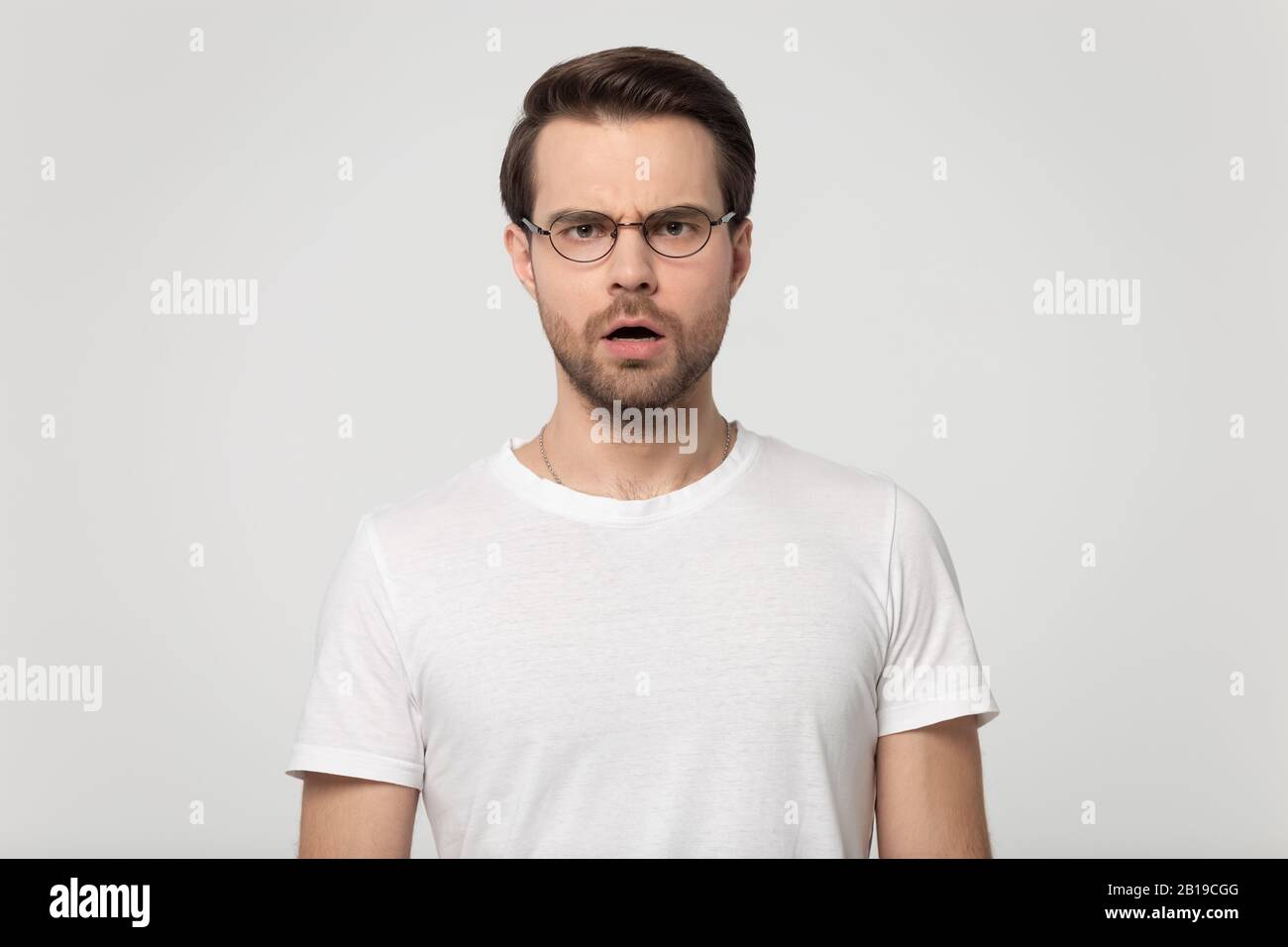 Dissatisfied unhappy millennial man looking angrily at camera head shot ...