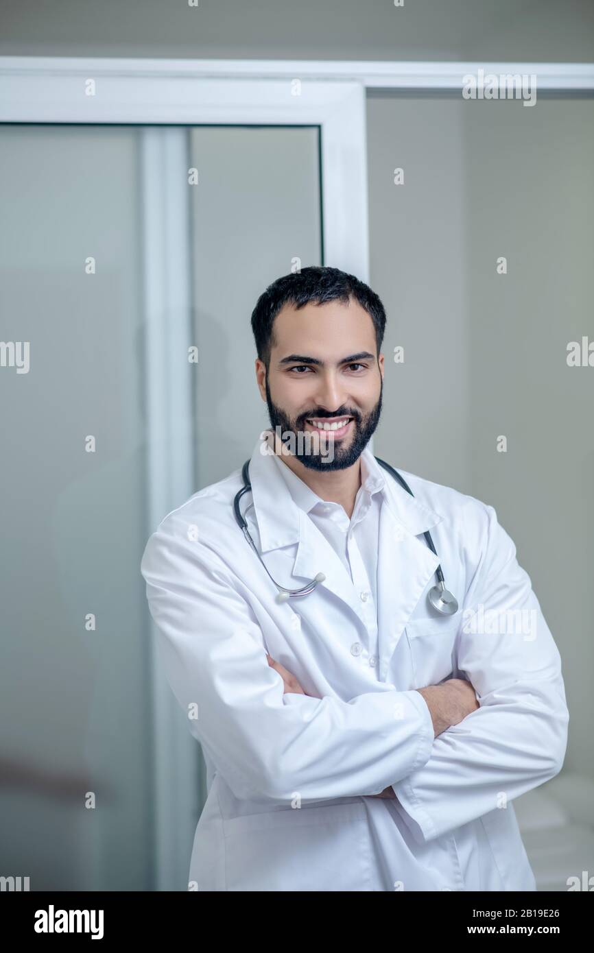Male doctor in a white robe standing with arms crossed Stock Photo - Alamy