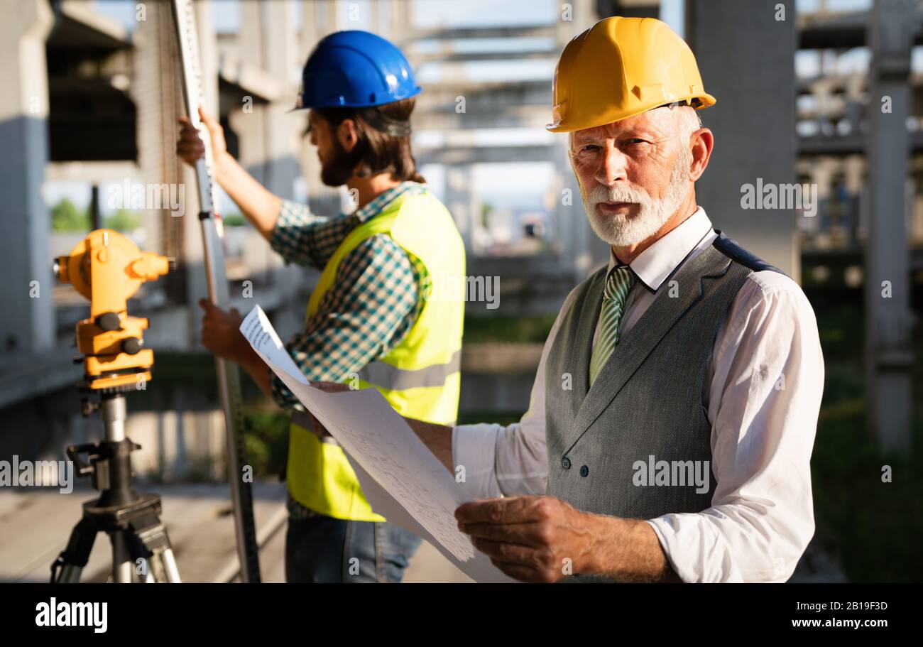 Male architects analyzing blueprint at construction site Stock Photo ...