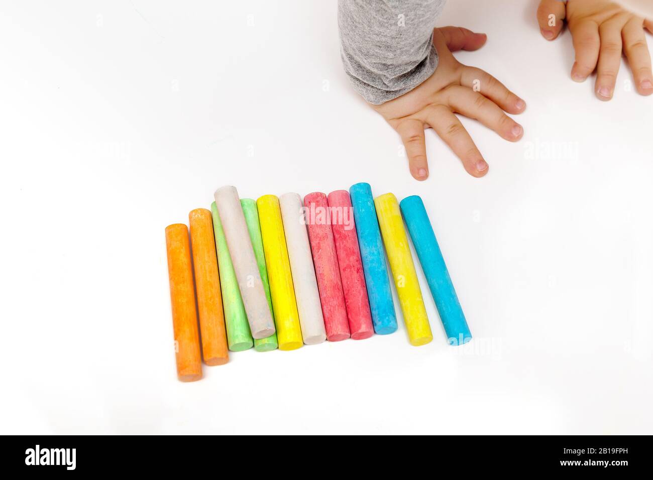 The child's hands are painted with colored crayons on a white sheet of ...