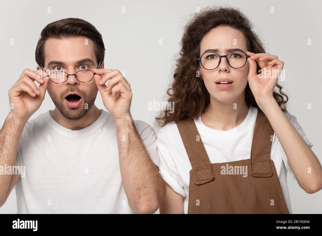 Surprised happy millennial man and woman looking closely at camera ...