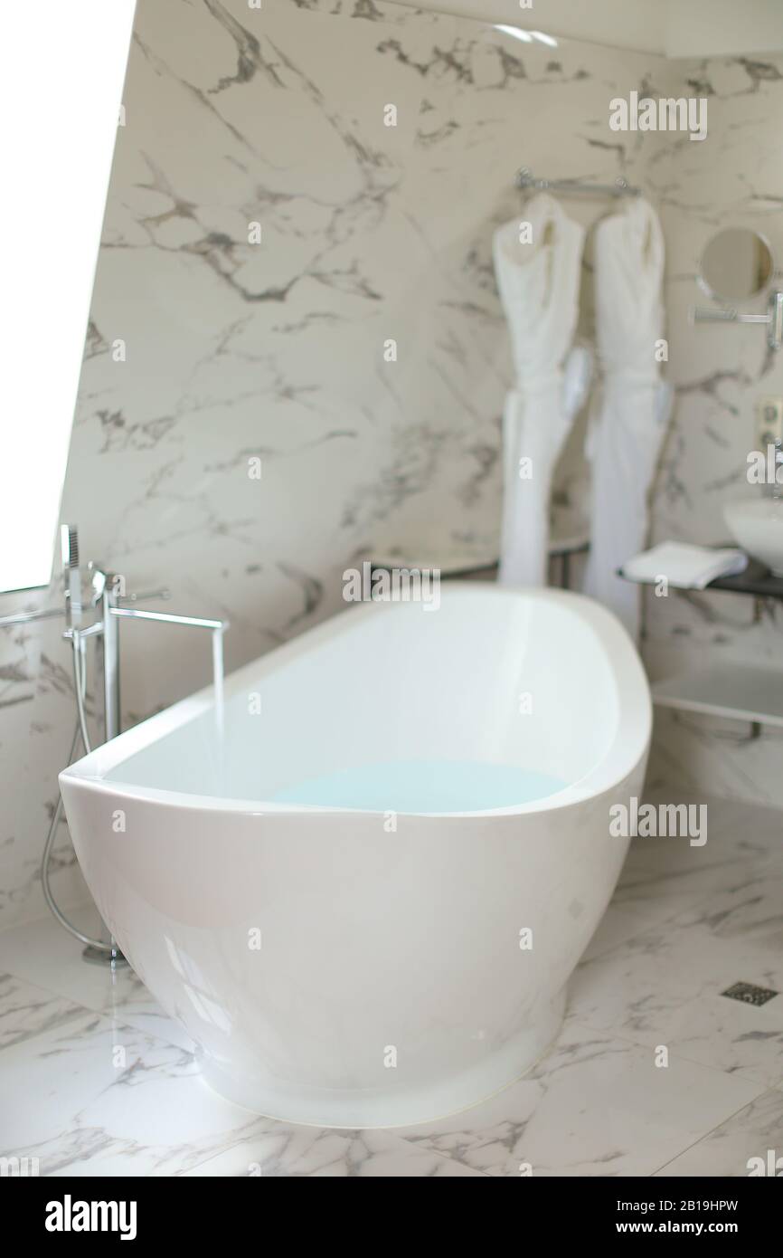 Modern white bathroom and ceramic bath near window Stock Photo - Alamy