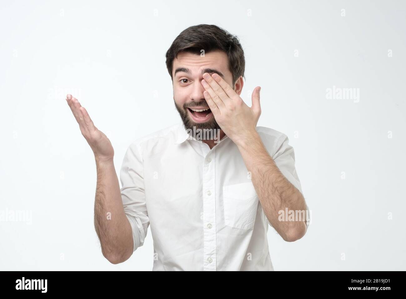 Young latin man wearing white shirt smiling cheerful playing peek a boo ...