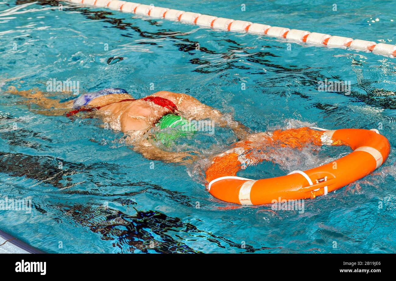 Lifeguard training in swimming pool. Man with lifeguard float swimming ...