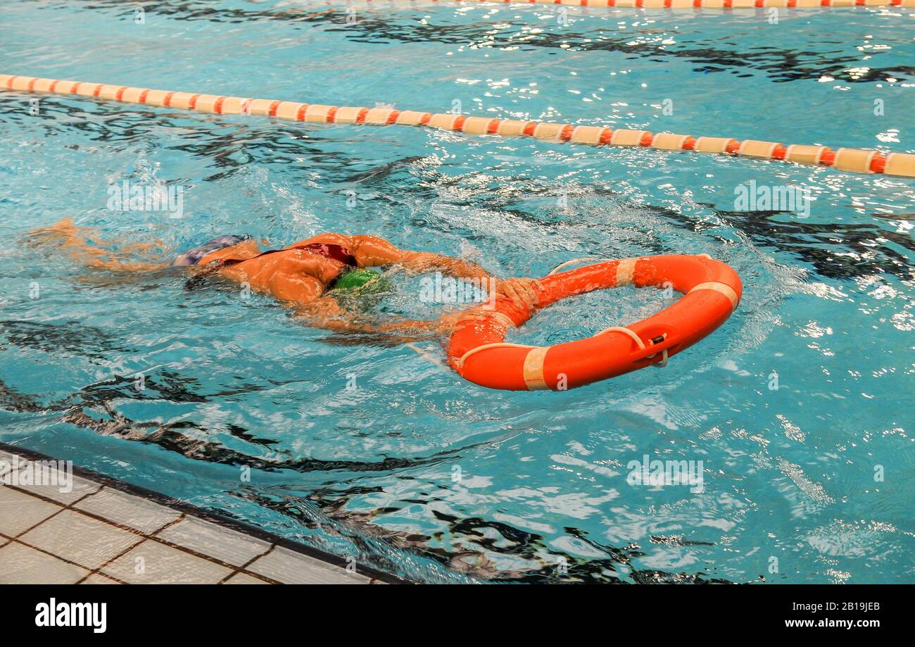 Lifeguard training in swimming pool. Man with lifeguard float swimming ...