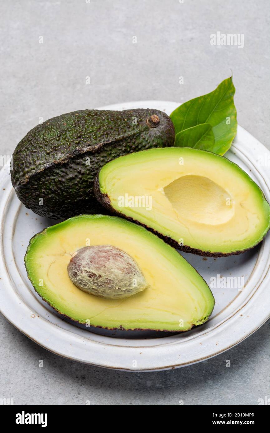 New harvest of fresh ripe hass avocado close cut in half with seed ...