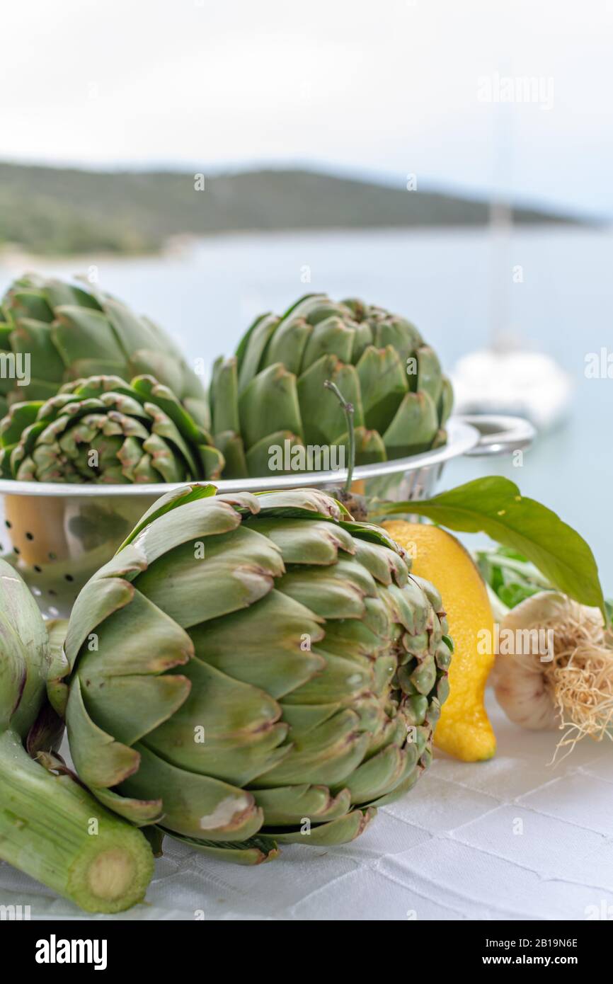 Cooking dinner with fresh green artichokes heads, tasty vegetarian food ...