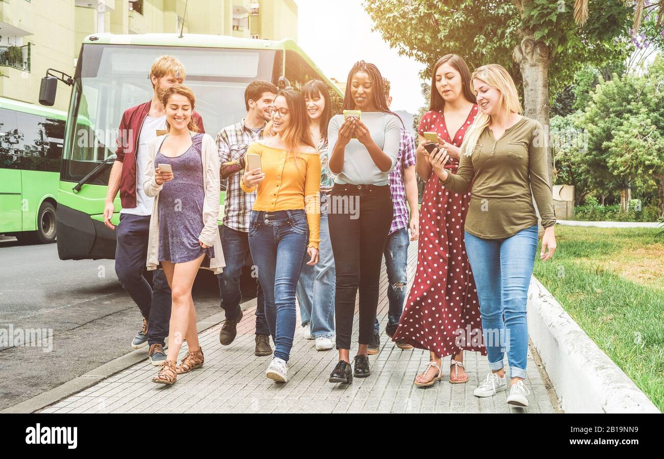 Happy students friends using smartphones at bus station - Young ...