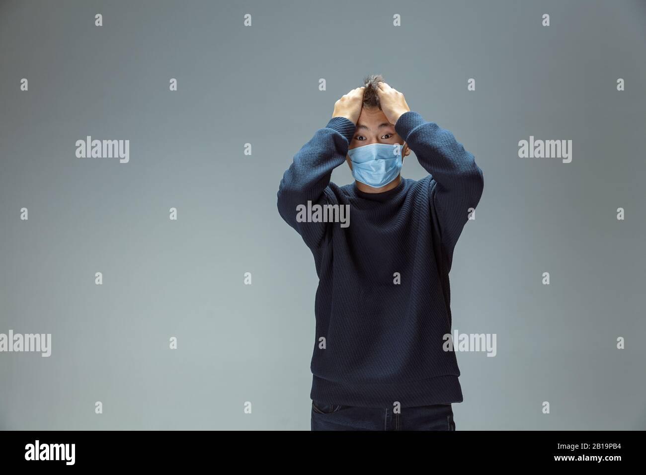 Sad, upset. Chinese man in blue protective mask posing. Prevention ...