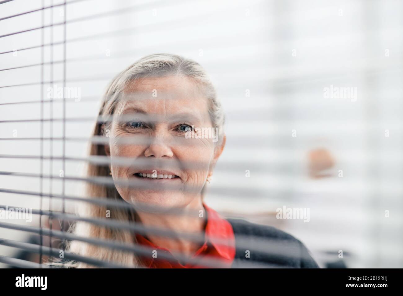 through the blinds. successful businesswoman looking through office ...