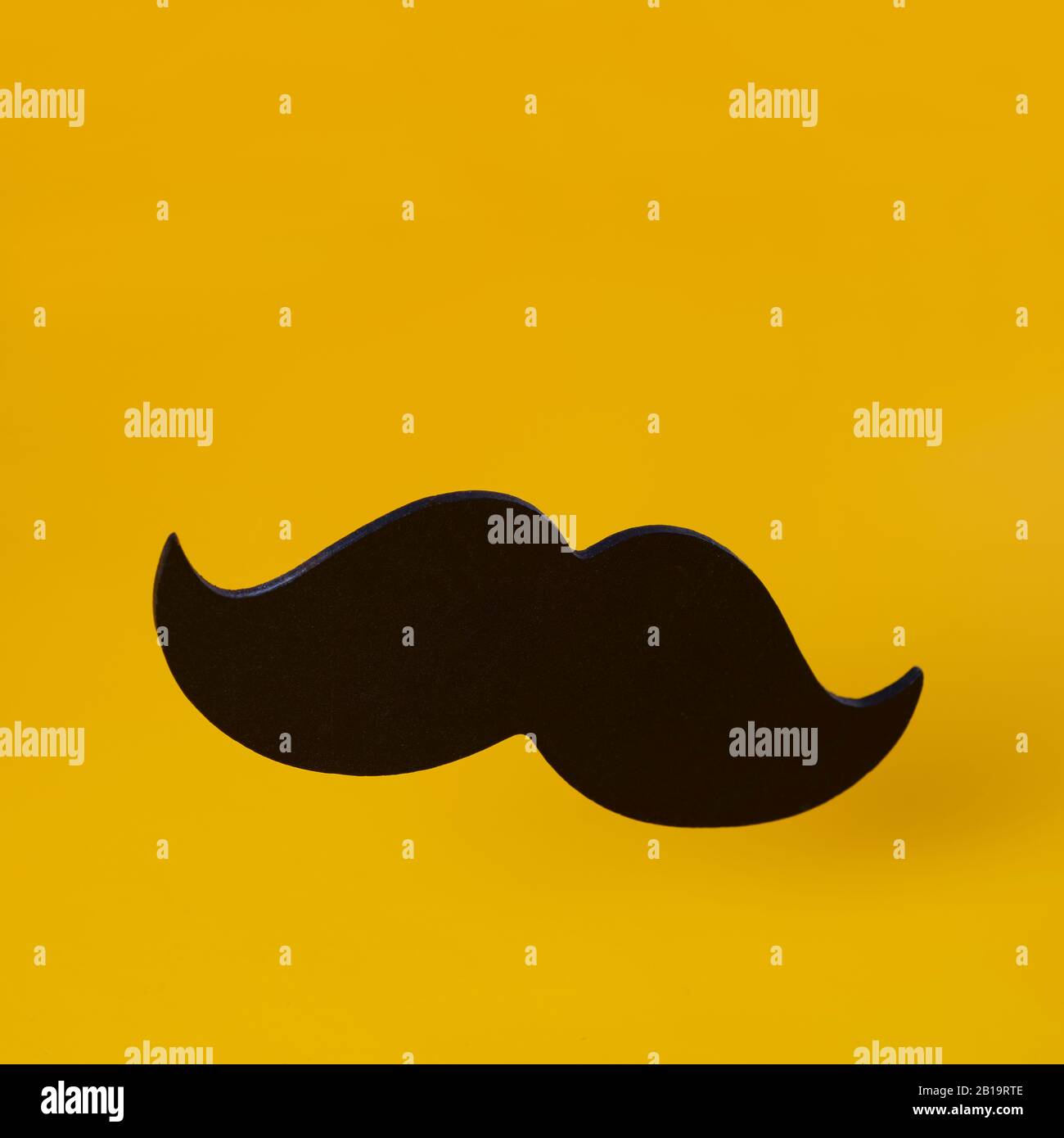 closeup of a black moustache on a yellow background with some blank ...