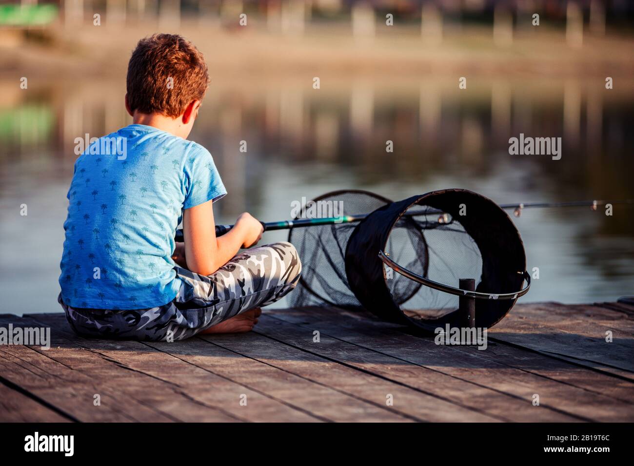The boy with a fishing rod. Cute child fishing on a lake in a sunny ...